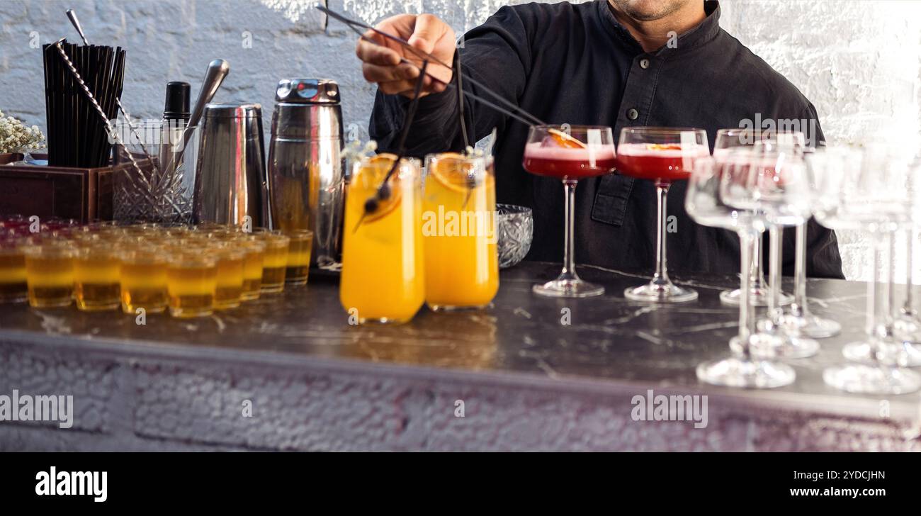 Bartender is preparing cocktails at bar. Man is mixing colorful drinks ...