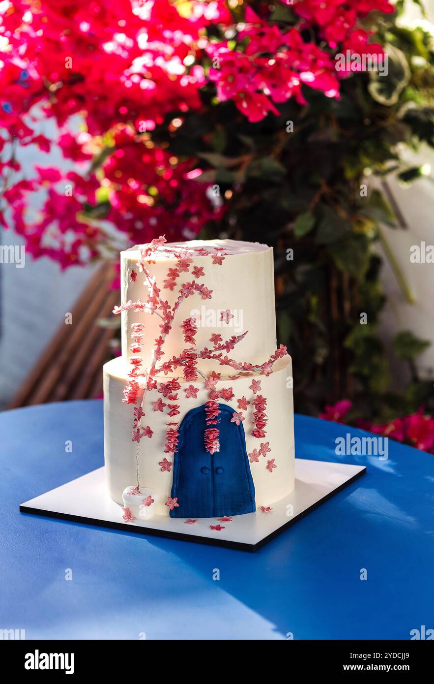 A cute white two-tiered delicious cake on a blue table. The sweetness ...