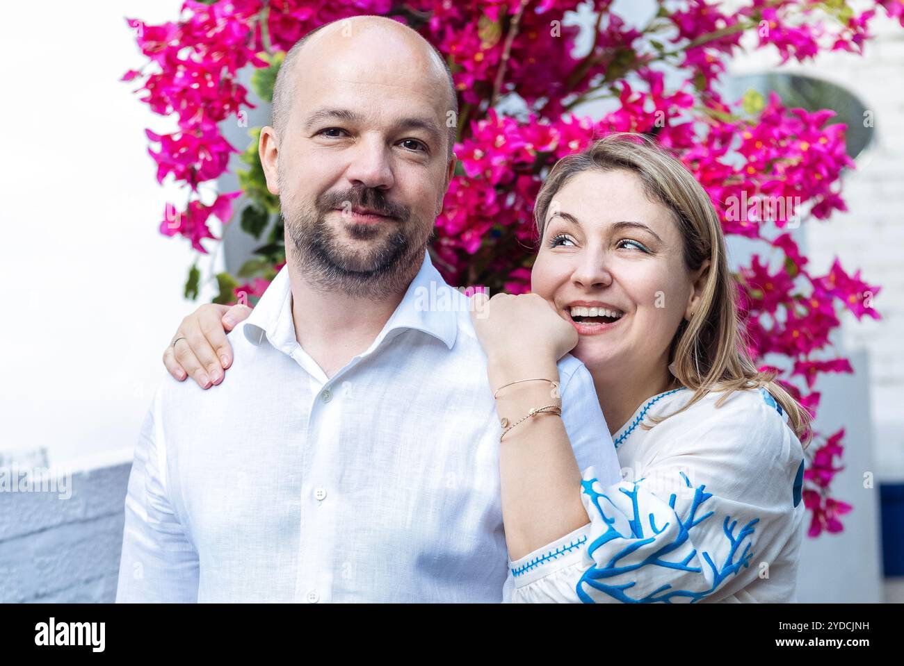 A young married couple poses at an outdoor festive event. A laughing ...
