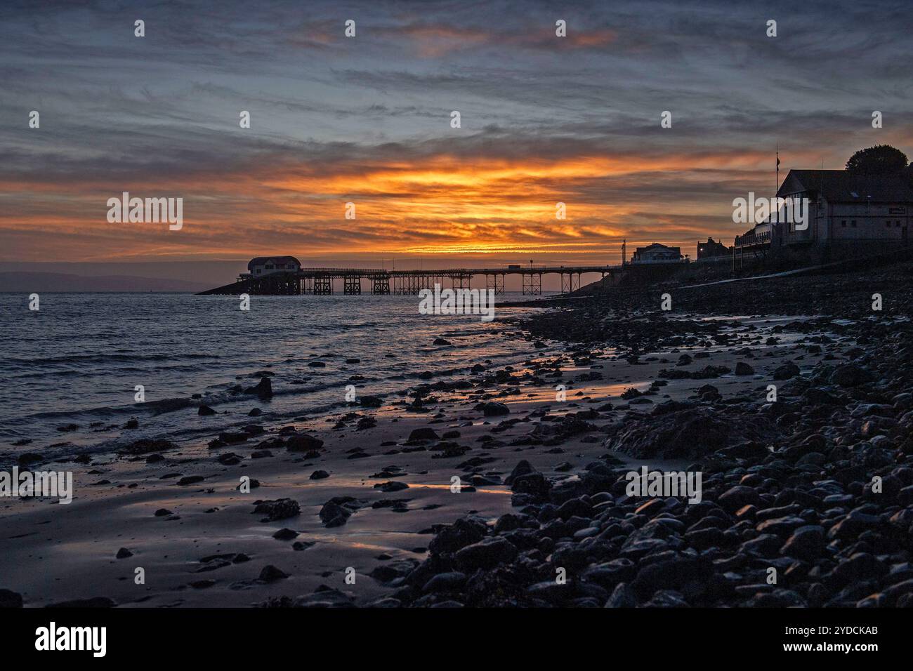 The sun rises this morning as people walk across Mumbles Pier which was ...
