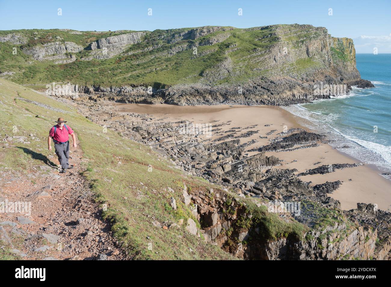 Man walking allong footpath under Carboniferous limestone cliff at ...