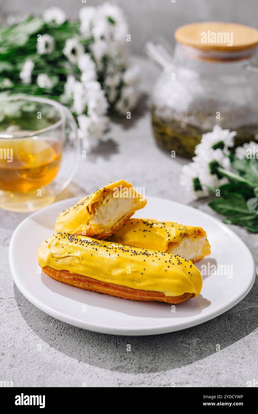 Fresh tasty eclair on white plate and cup of tea Stock Photo - Alamy