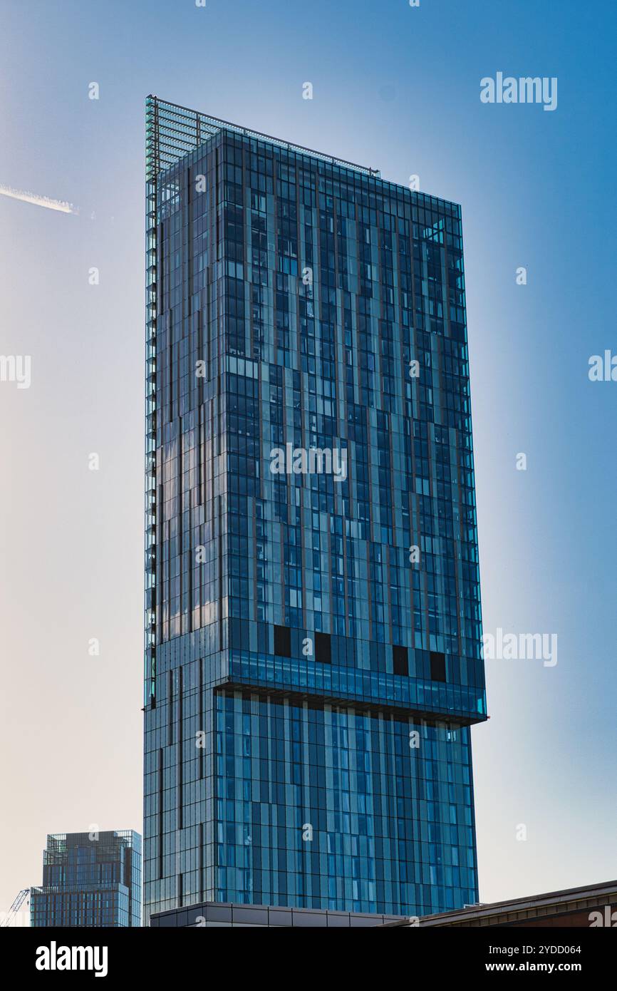 A tall, modern skyscraper with a glass facade against a clear blue sky ...