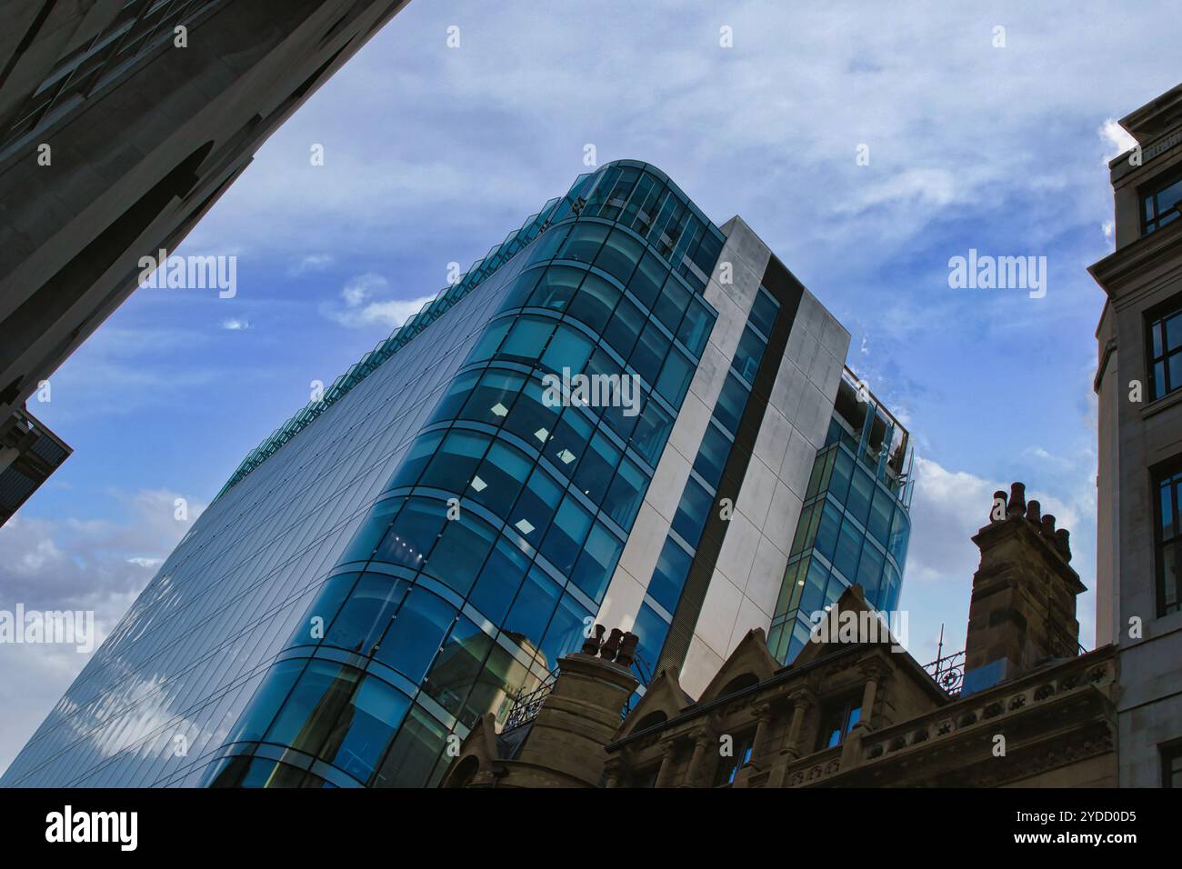 A low angle view of a modern glass and concrete skyscraper with blue ...