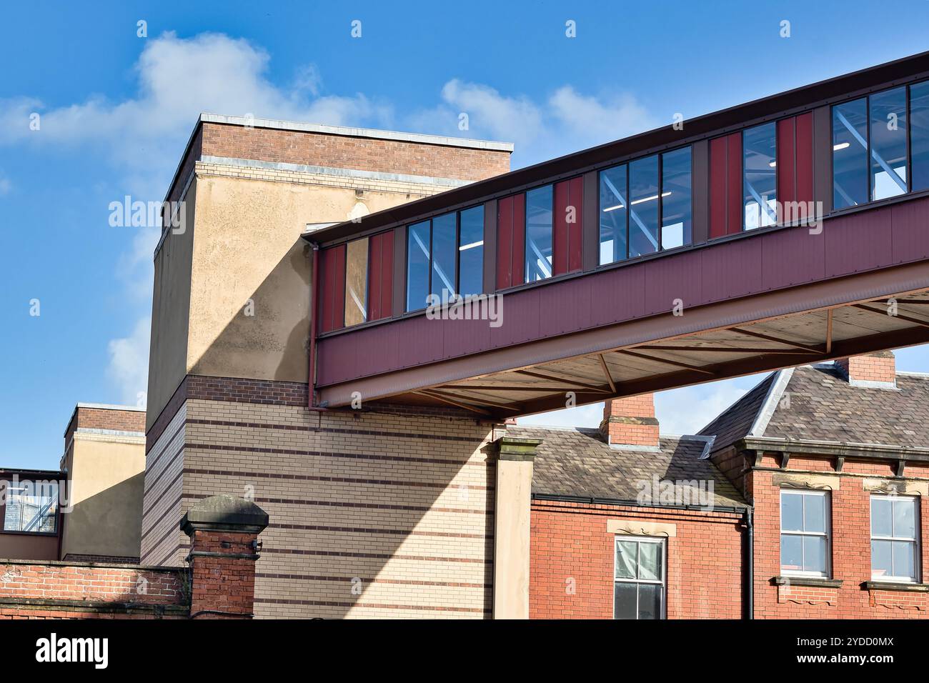 A covered walkway, supported by metal beams, connects two brick ...