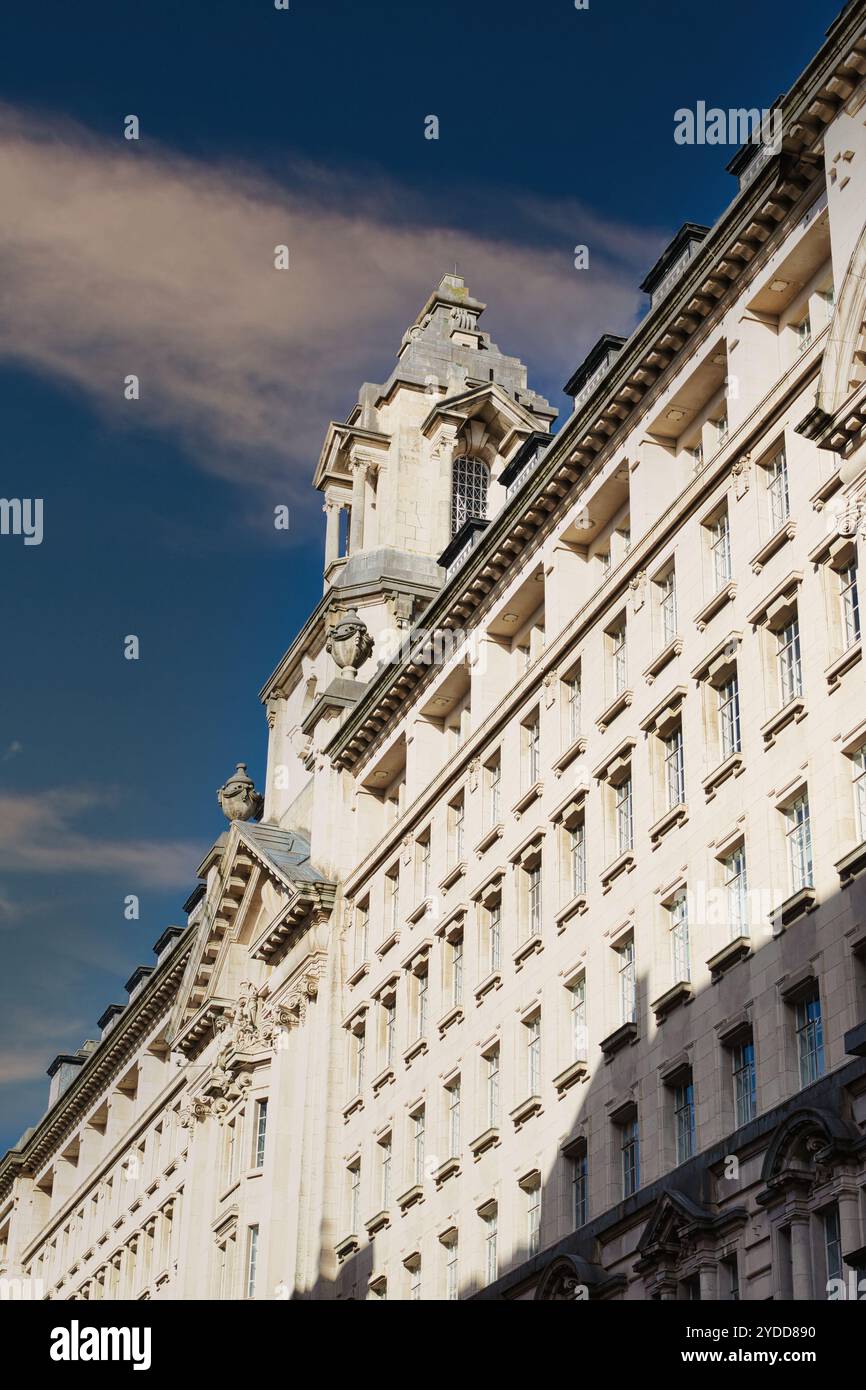 A low-angle shot of a tall, white building with a row of windows and ...