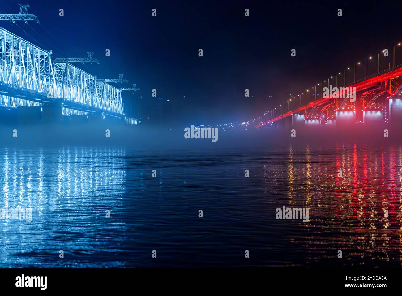 Two illuminated bridges, one blue and one red, stretch over a river at ...