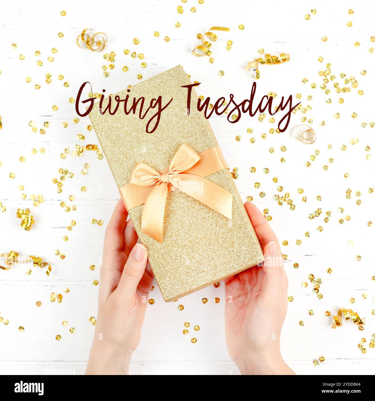 Giving Tuesday concept with golden box in hands Stock Photo - Alamy