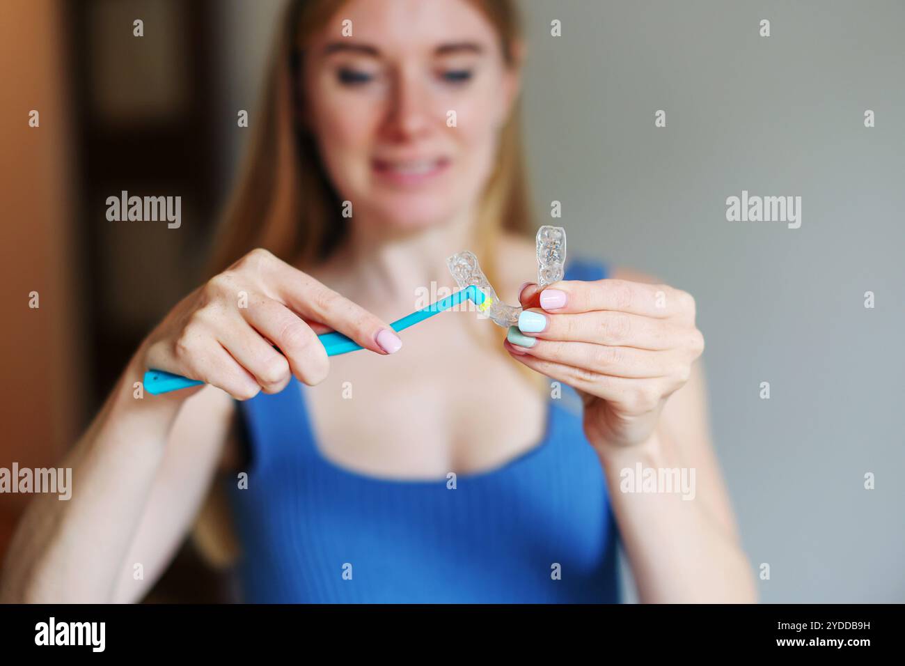 girl cleans an invisible mouth guard with a toothbrush to correct her ...