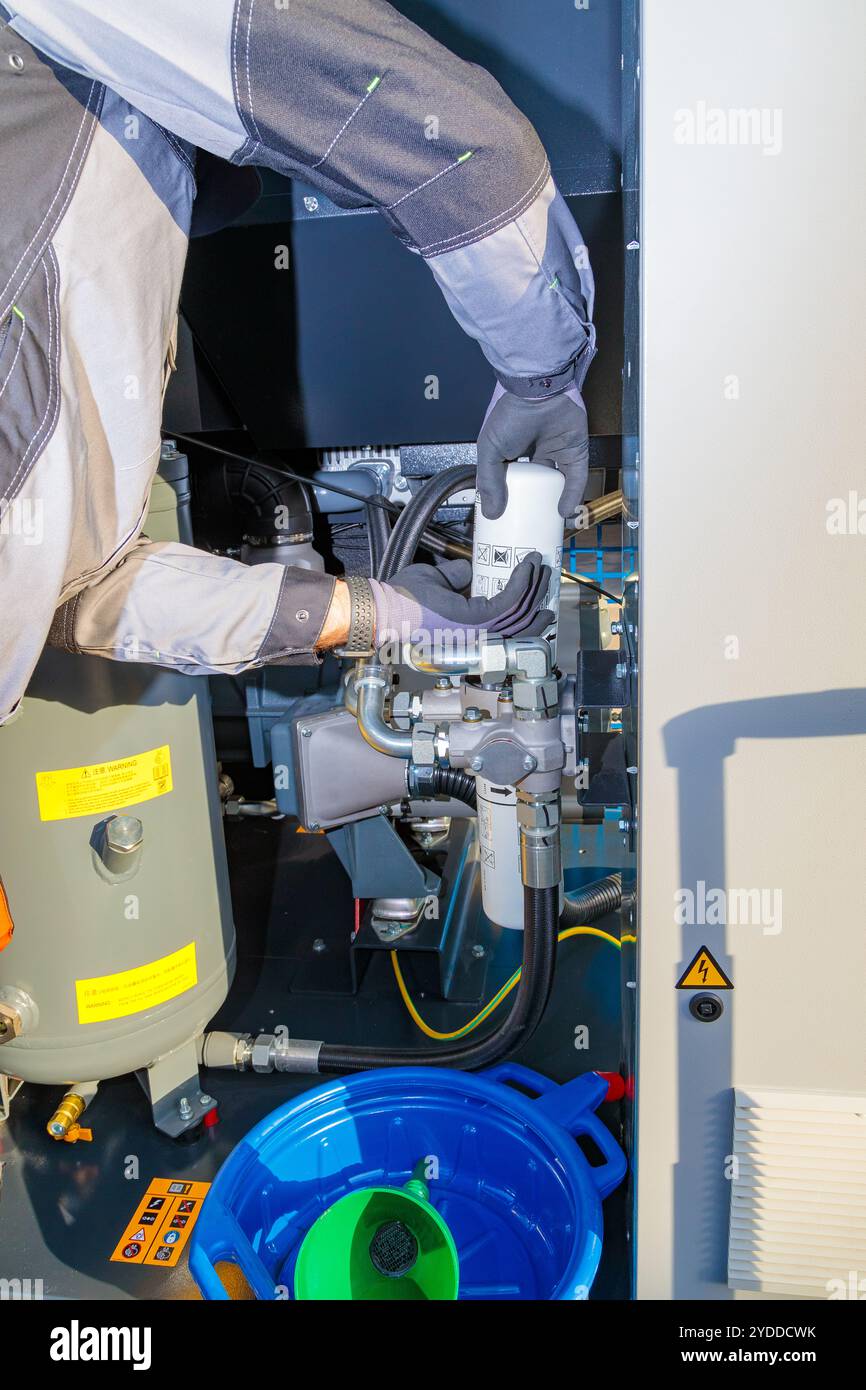 Technician replacing oil filter in industrial air compressor during ...