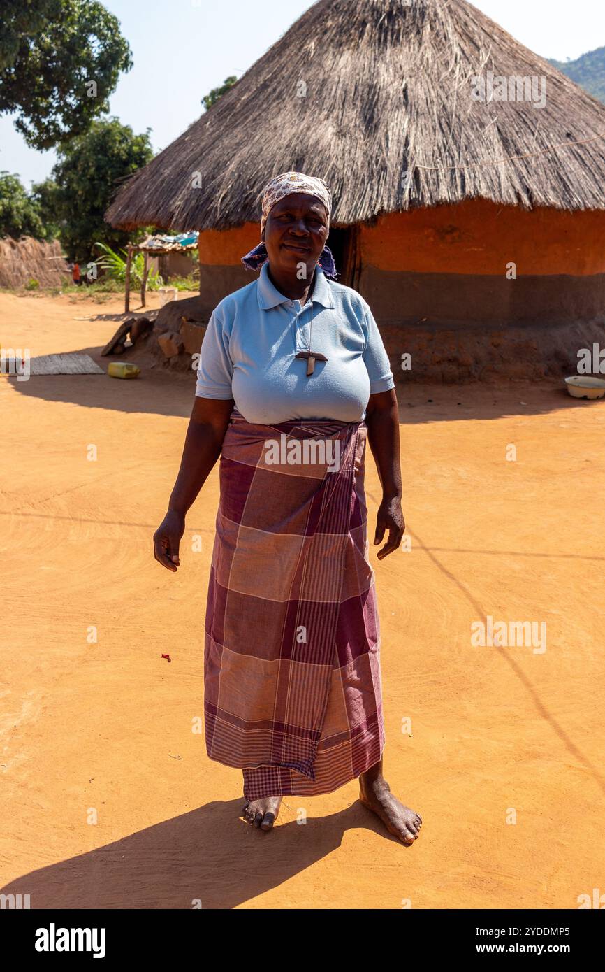 Woman standing in front of a traditional African mud hut, build from ...