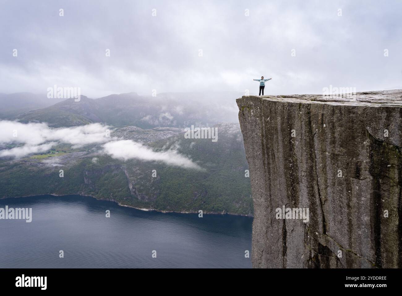 A woman on top of Preikestolen cliff, also known as Pulpit Rock, in the ...