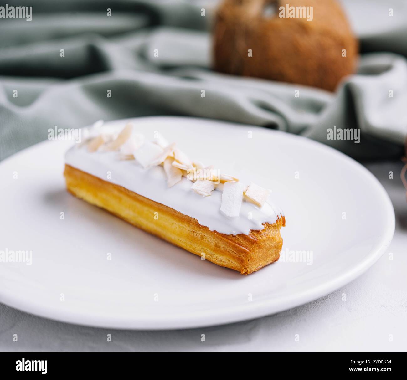 French eclair with coconut on plate Stock Photo - Alamy