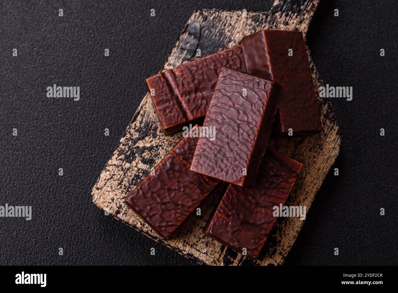 Rectangular chocolate candies with mousse and waffles on a dark ...