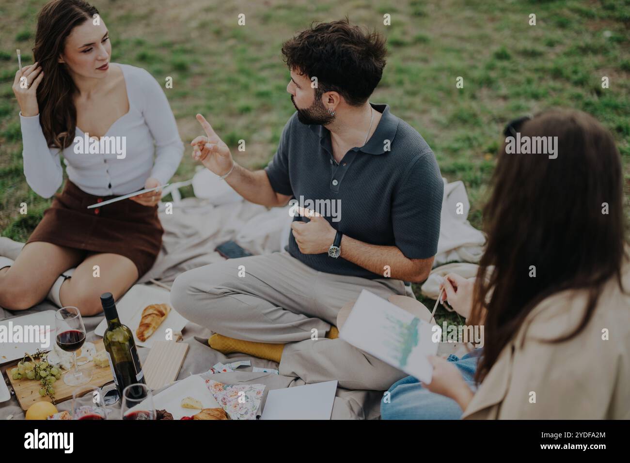 A group of friends engages in a creative picnic, enjoying art and ...