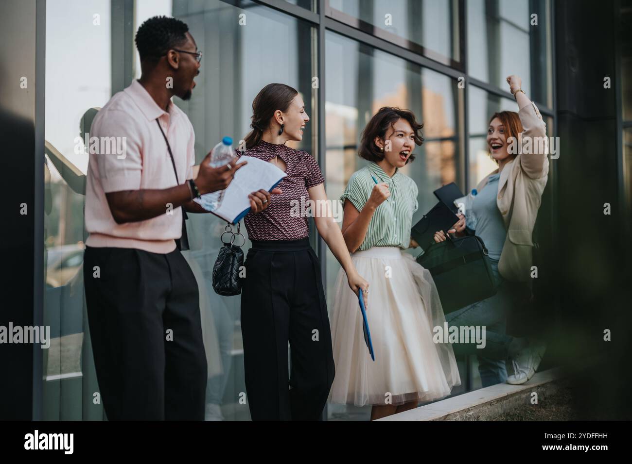 Diverse colleagues celebrating success outside a modern office building ...