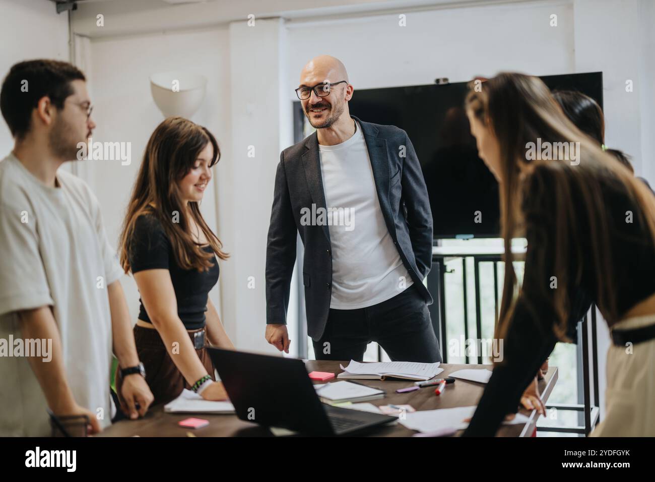Group of students collaborating with supportive professor in modern ...