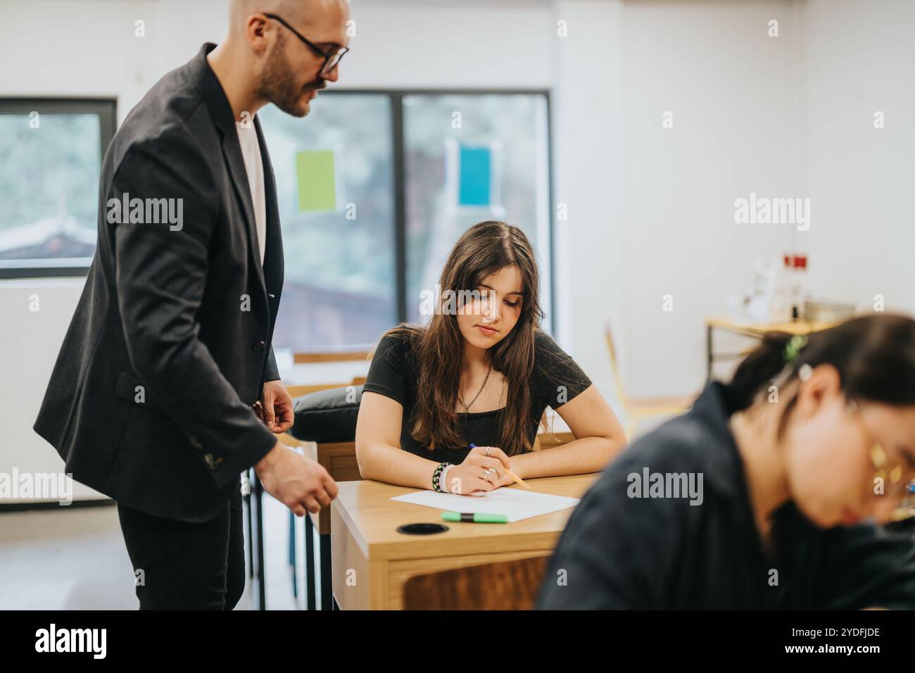 Teacher assisting students in a collaborative classroom setting Stock ...