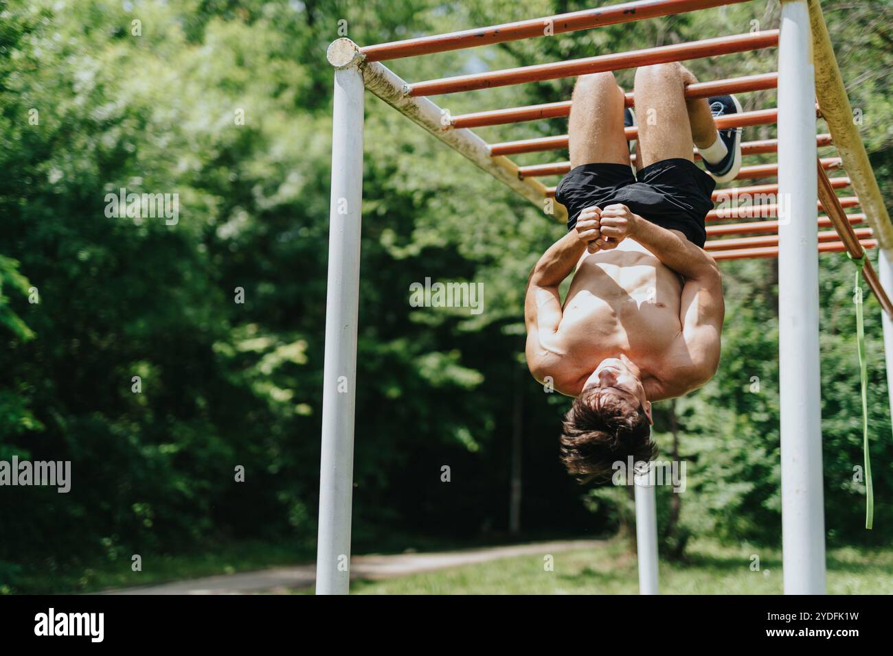 Fit male athlete working out in park hanging upside down on monkey bars Stock Photo - Alamy