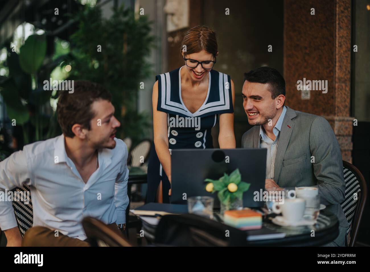 Business colleagues collaborating over a laptop in a modern cafe ...