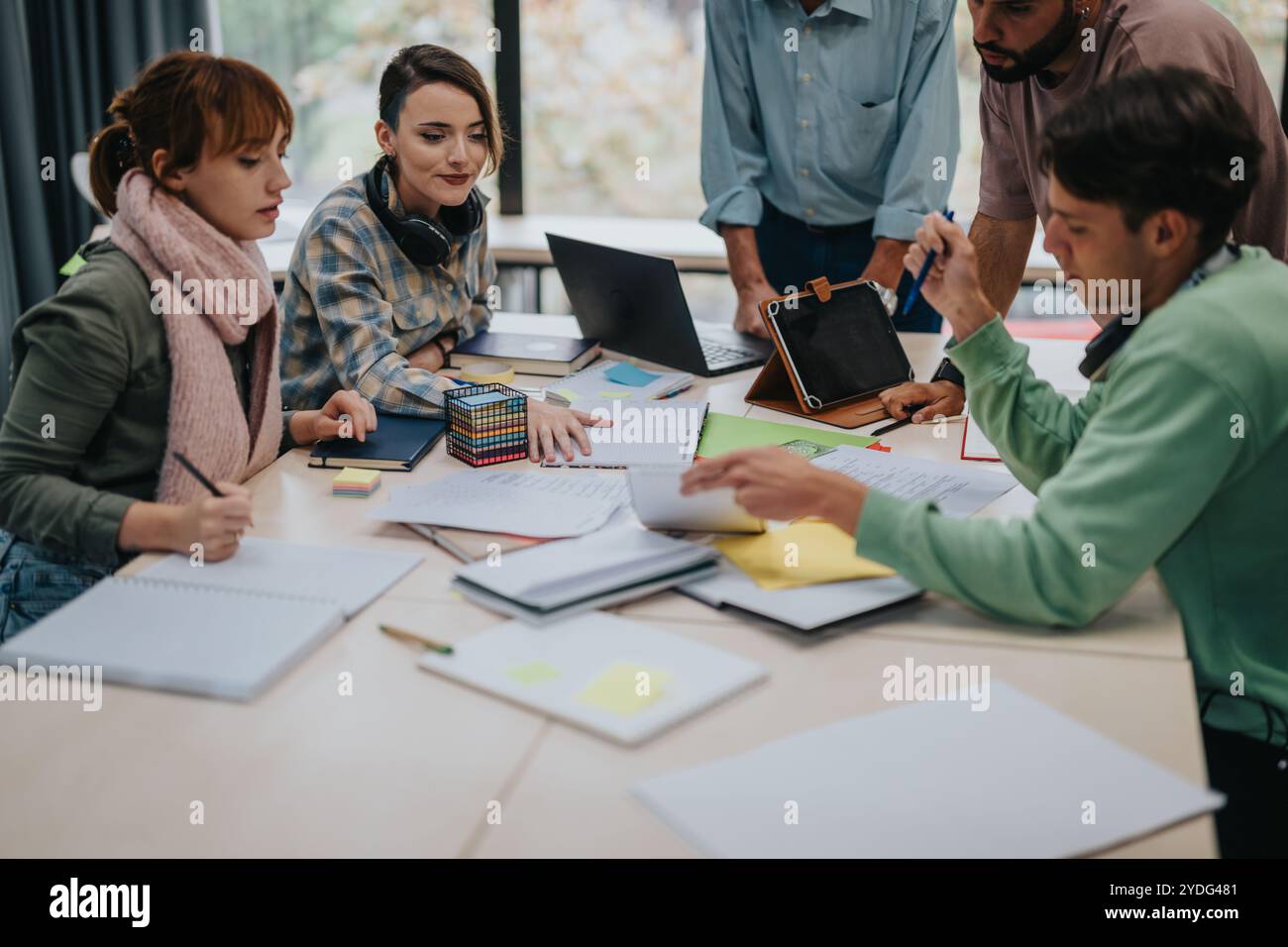 University students collaborating with professor on academic project ...