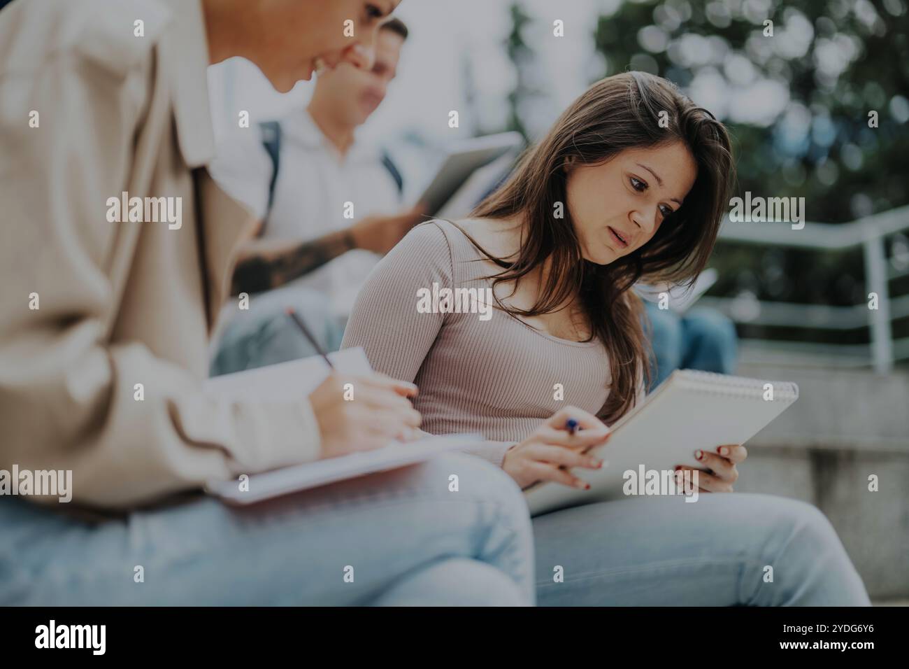 Students collaborating and studying together in urban outdoor setting ...