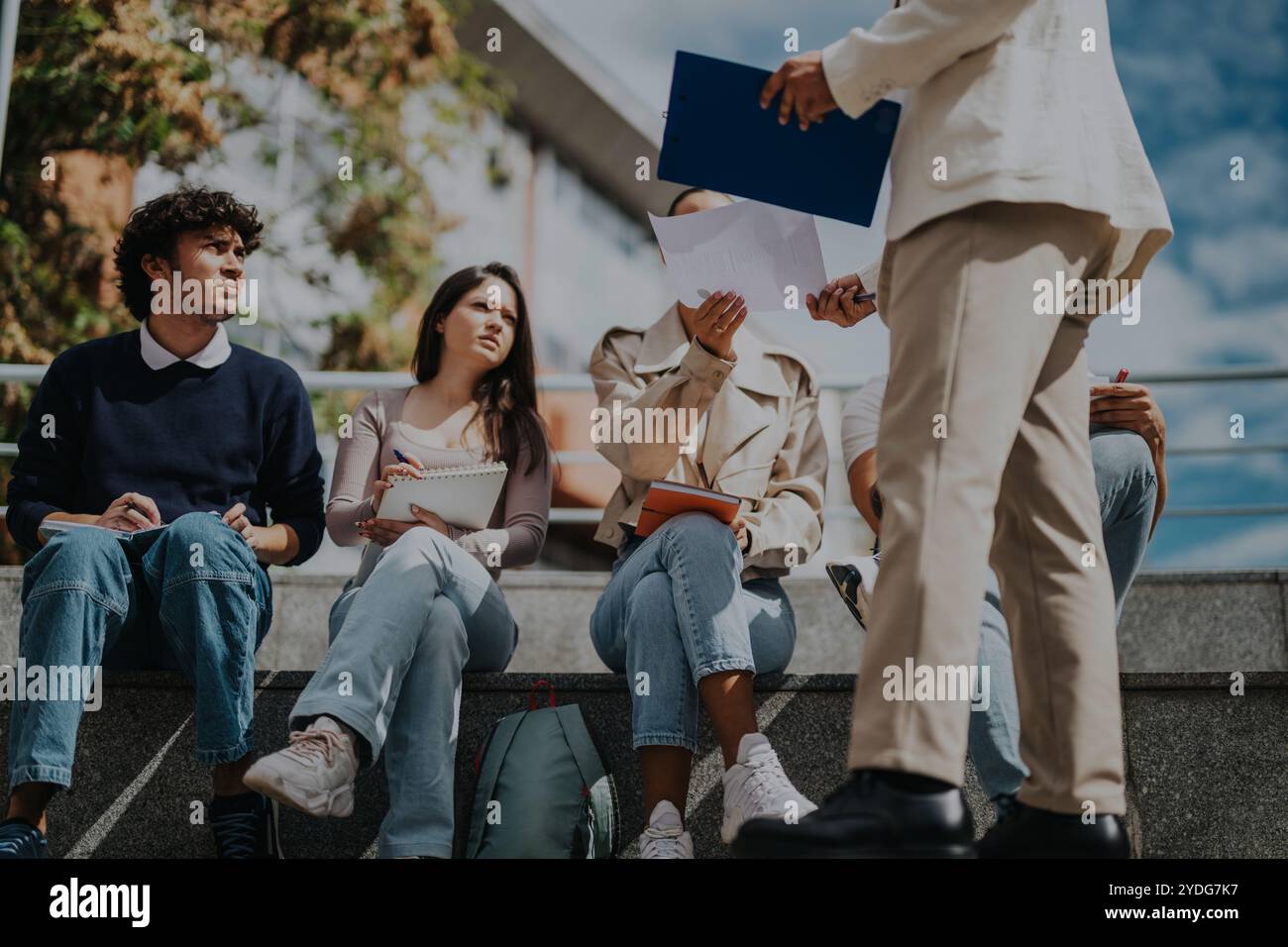 High school students collaborating with professor outside on campus ...