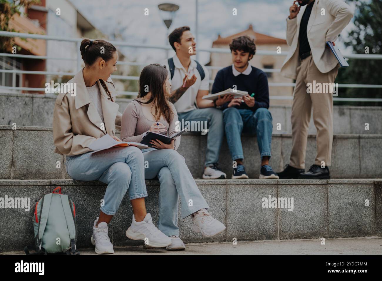Students collaborating outdoors with professor on stone steps Stock ...