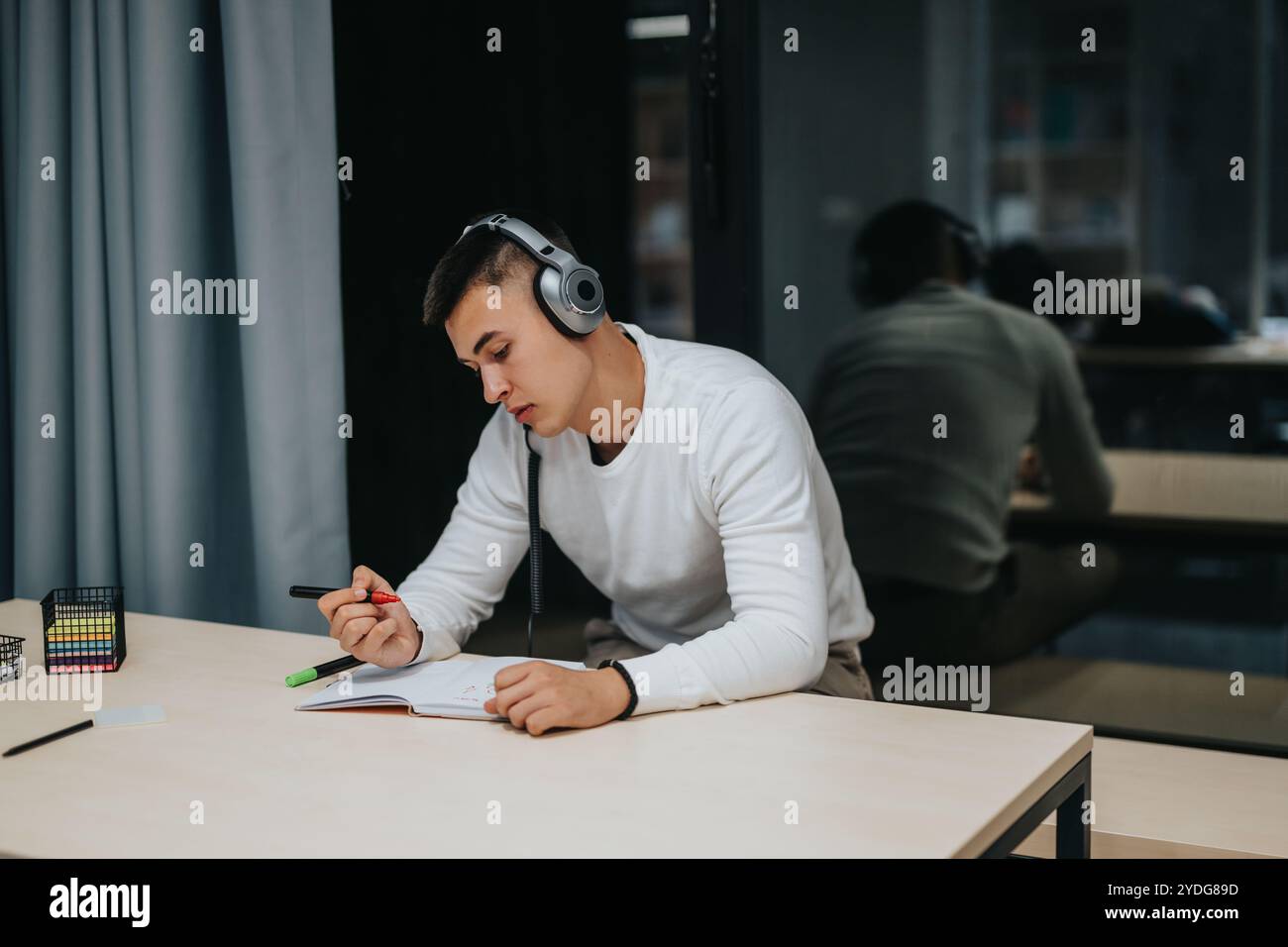 Student studying intently with headphones in a cozy classroom setting ...