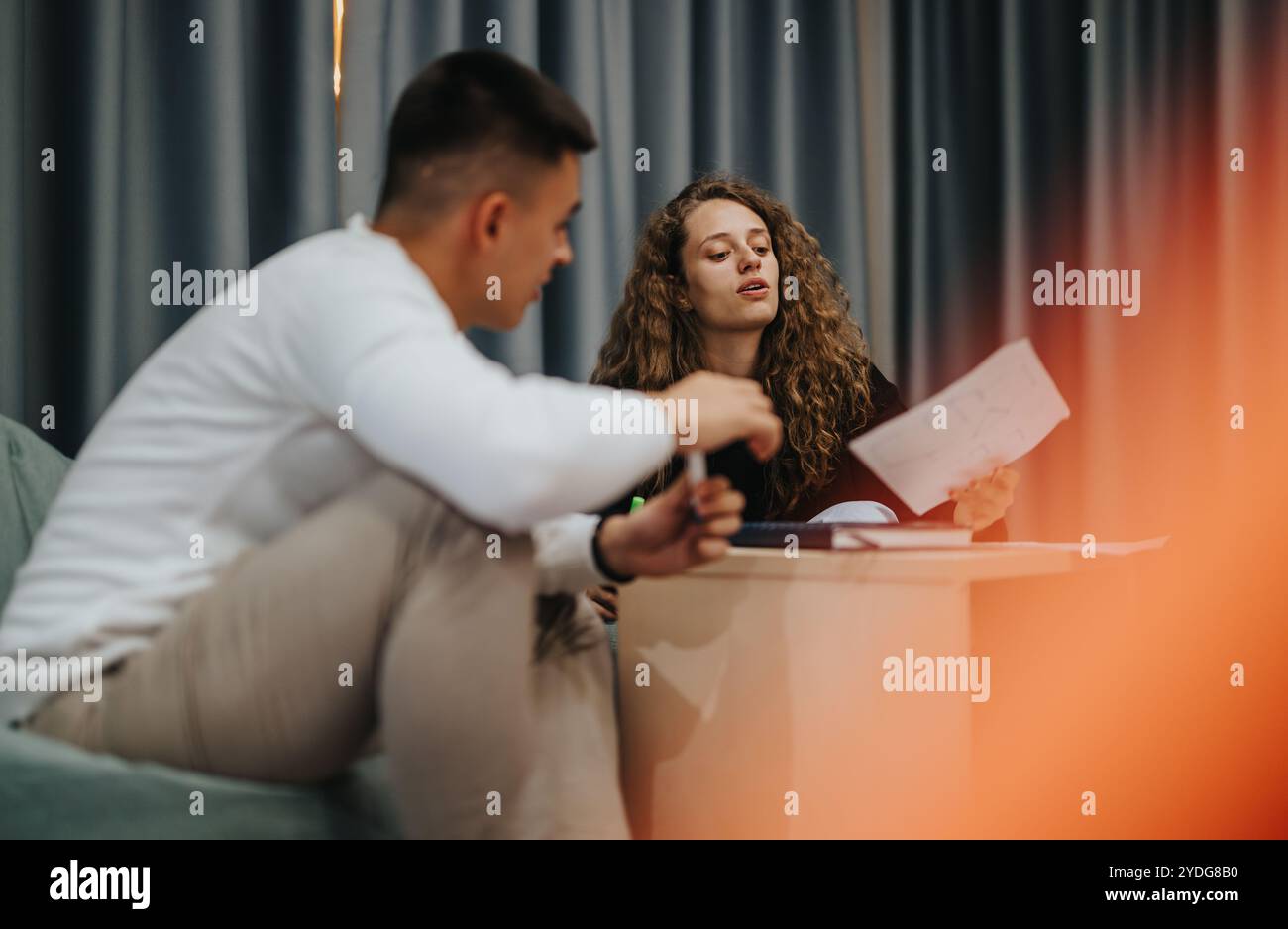 Two students engaged in a collaborative study session inside a cozy classroom setting with soft ...