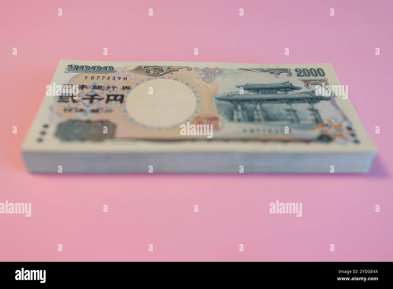 2000 yen banknotes placed against a delicate sakura pink backdrop ...