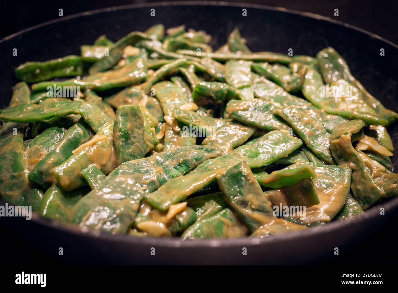 Sauteed flat beans in a pan with garlic, spices, and tahini The green ...