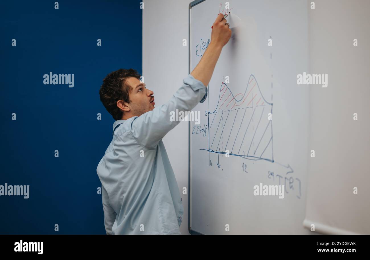 Young student writing mathematical equations on whiteboard in classroom ...