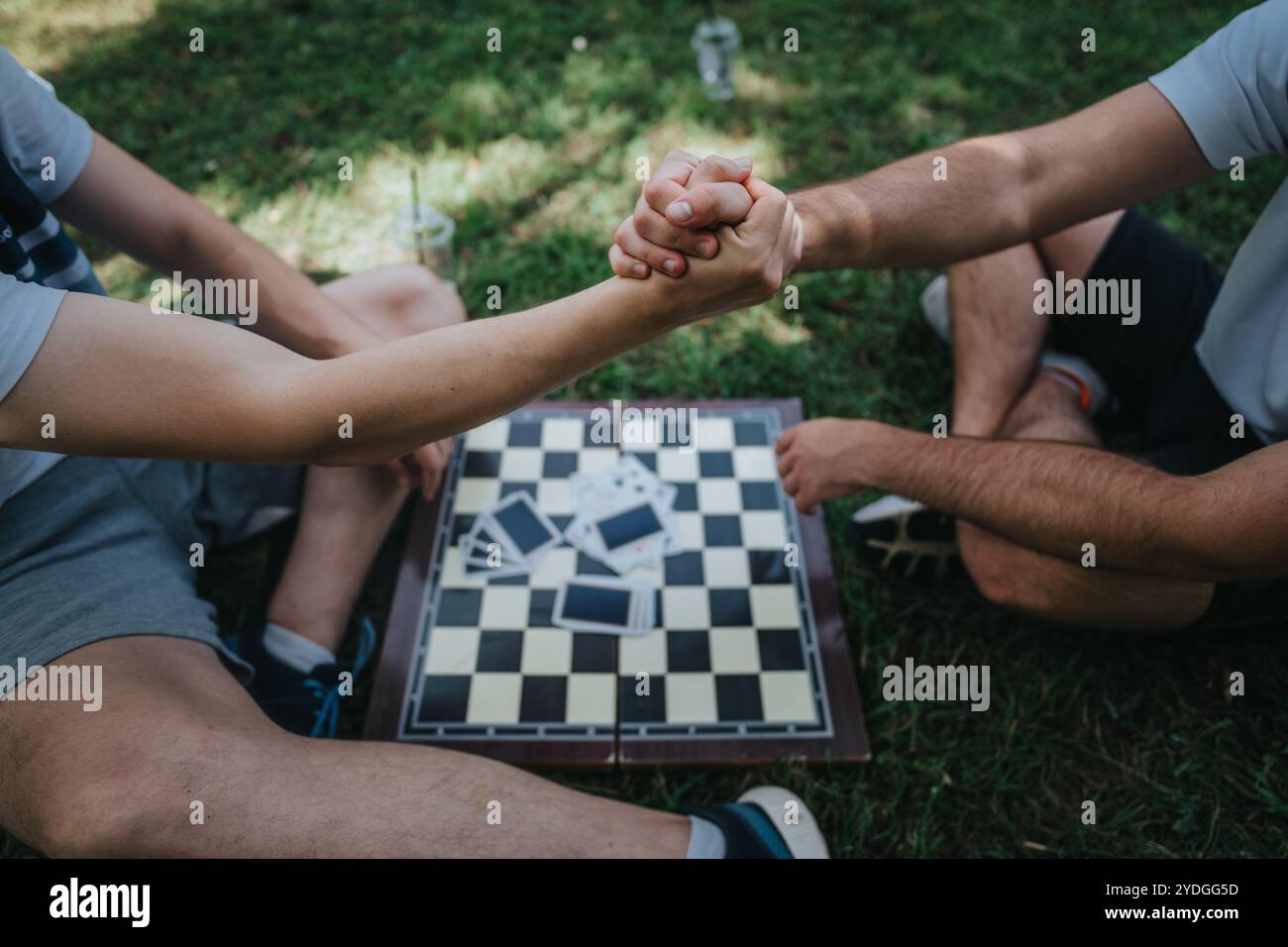 Friends arm wrestling in a park next to a chess board Stock Photo - Alamy