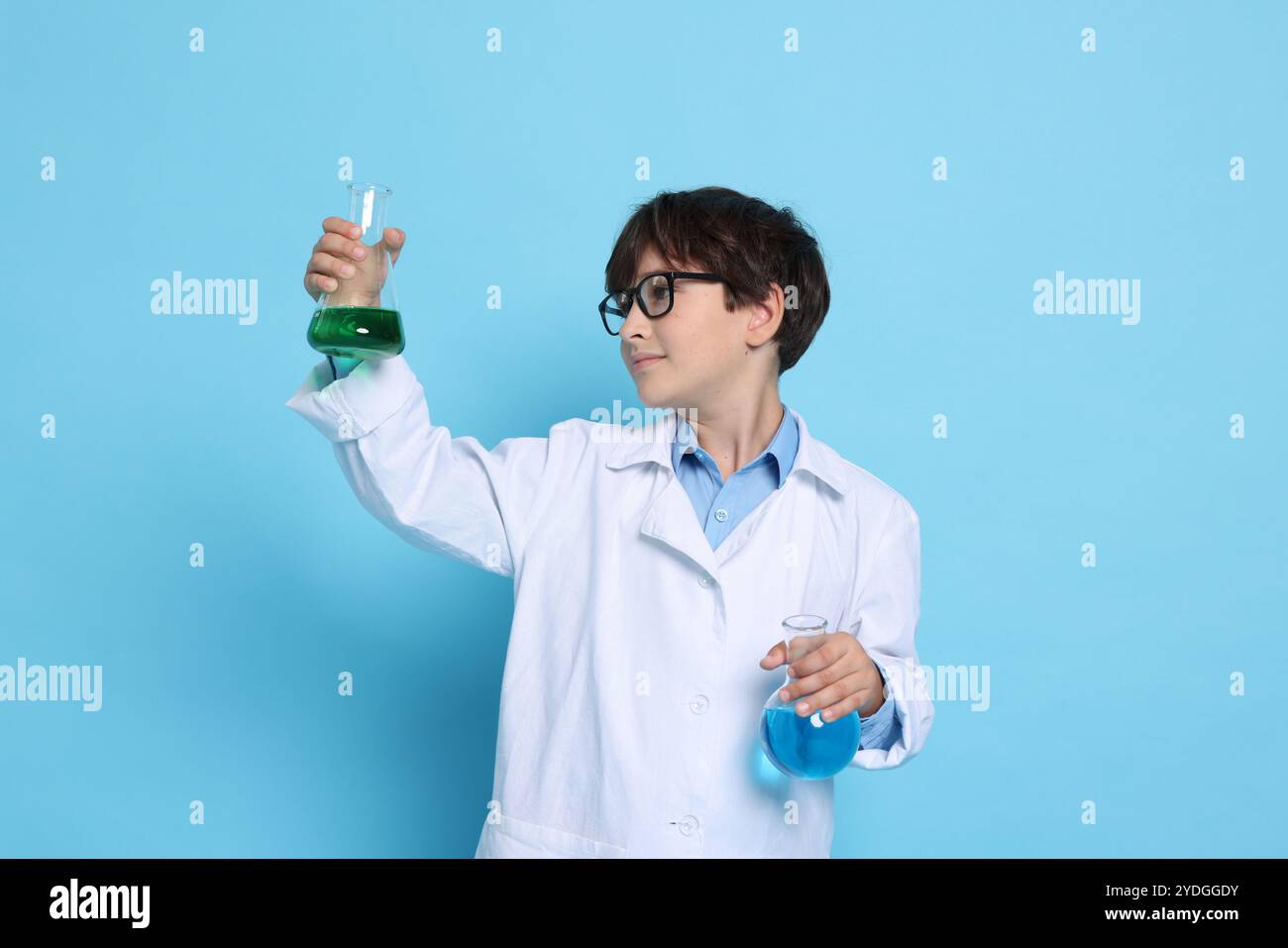Boy with glassware pretending to be scientist on light blue background ...