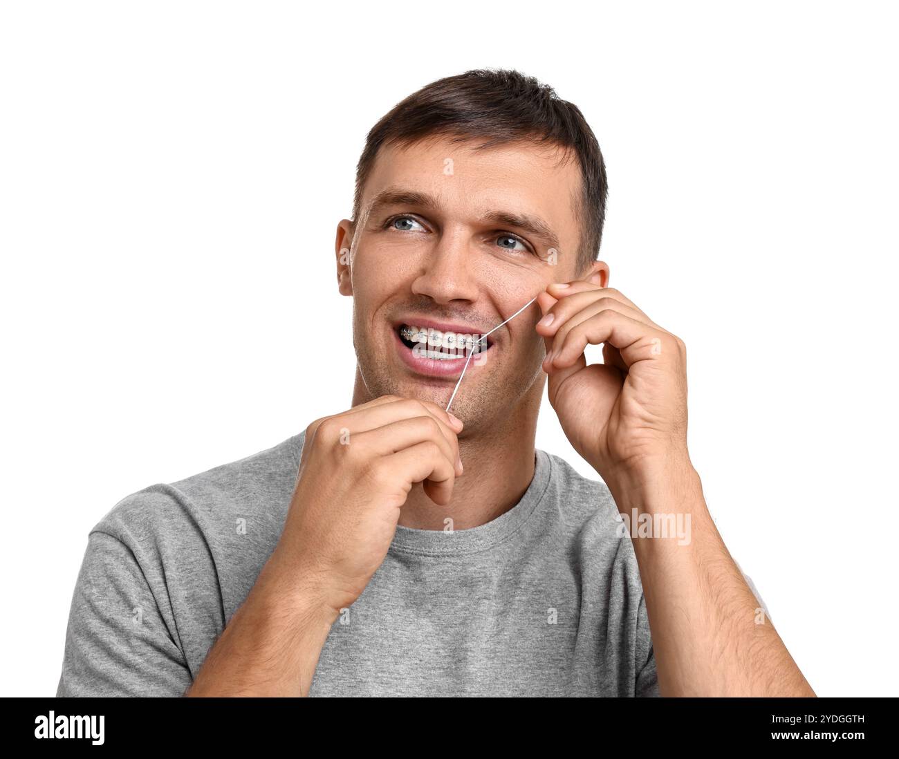 Man with braces cleaning teeth using dental floss on white background ...