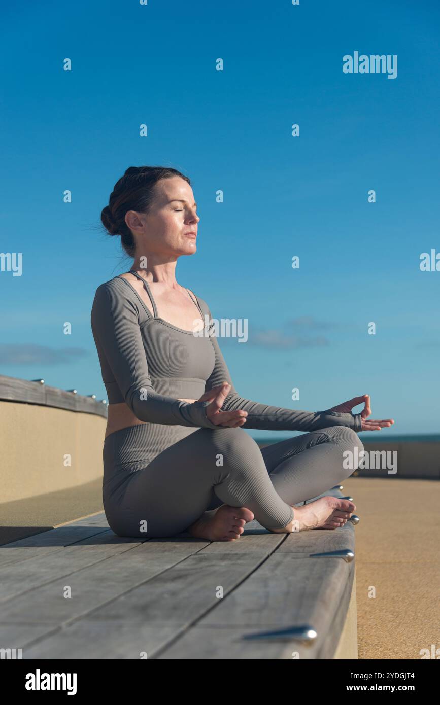 sporty woman sitting meditating practicing yoga outdoors on a concrete ...