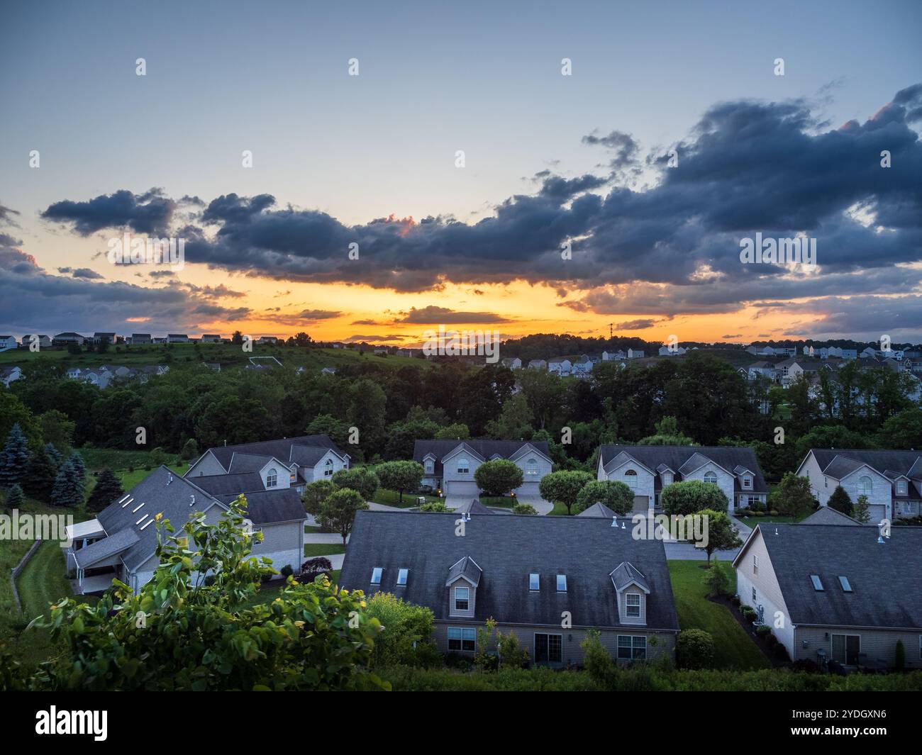 A vibrant orange sunset illuminates the sky with hues of gold and pink ...