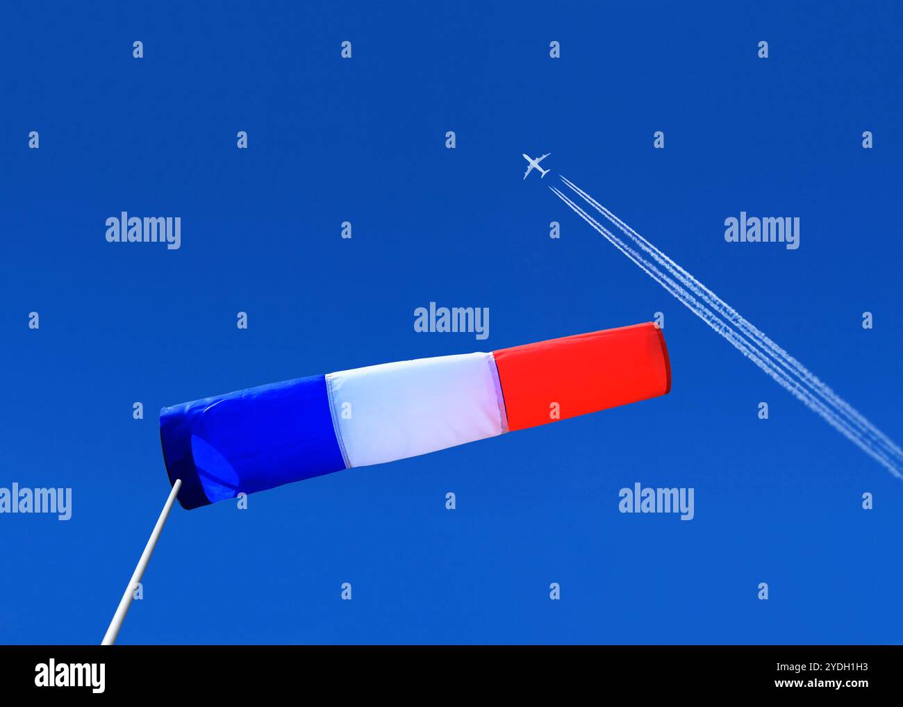 passenger plane with vapour trails high in the blue sky with french ...