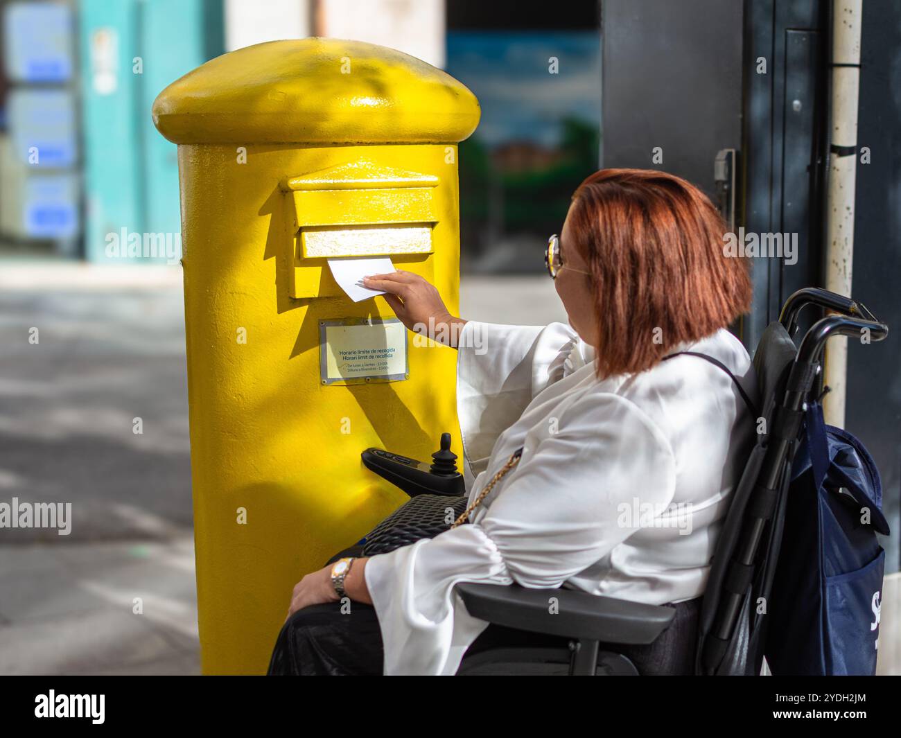 Woman Using Electric Wheelchair to Send a Letter in Public Mailbox ...