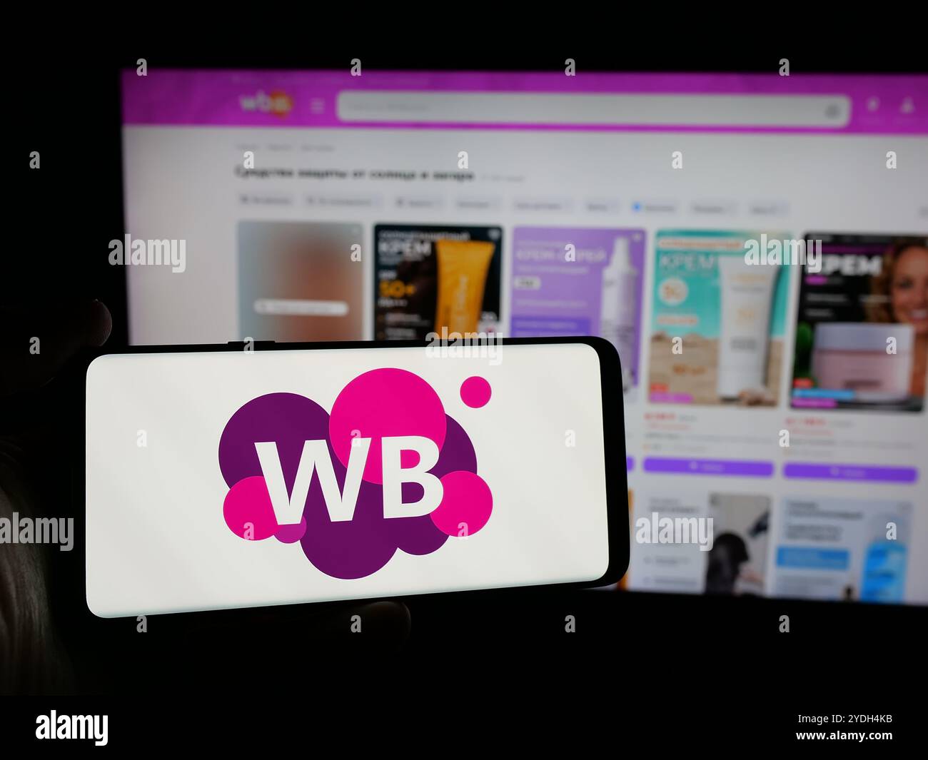 Person holding smartphone with logo of Russian e-commerce company Wildberries on screen in front ...
