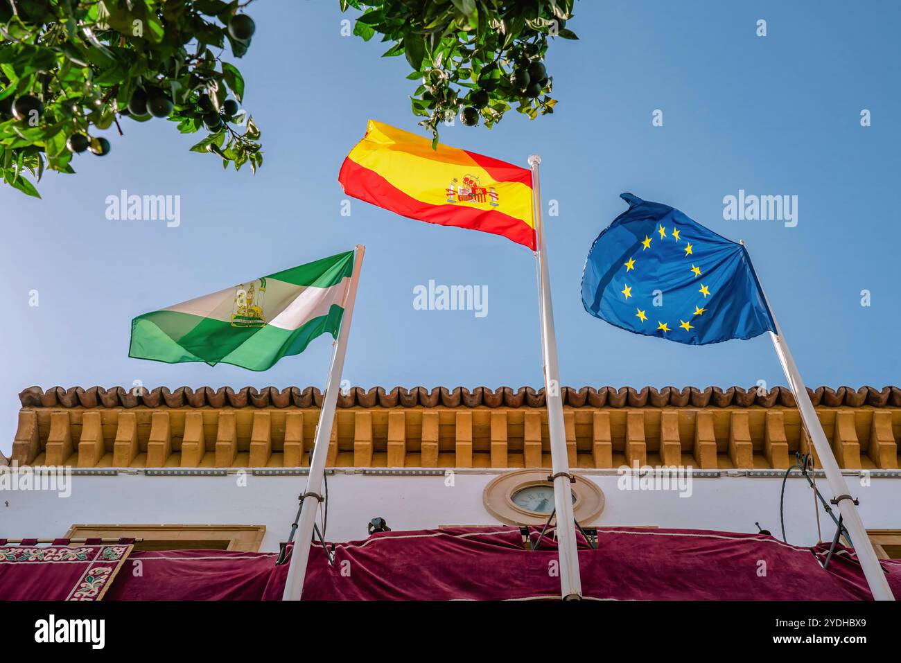 Vibrant flags wave above a white building in Andalusia, adding color to ...