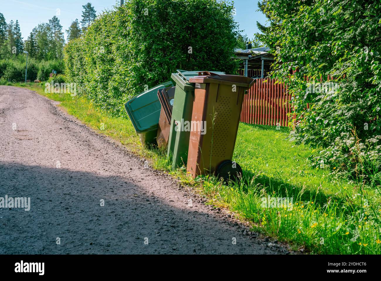 Overflowing trash cans are lying on the ground next to a gravel road in ...