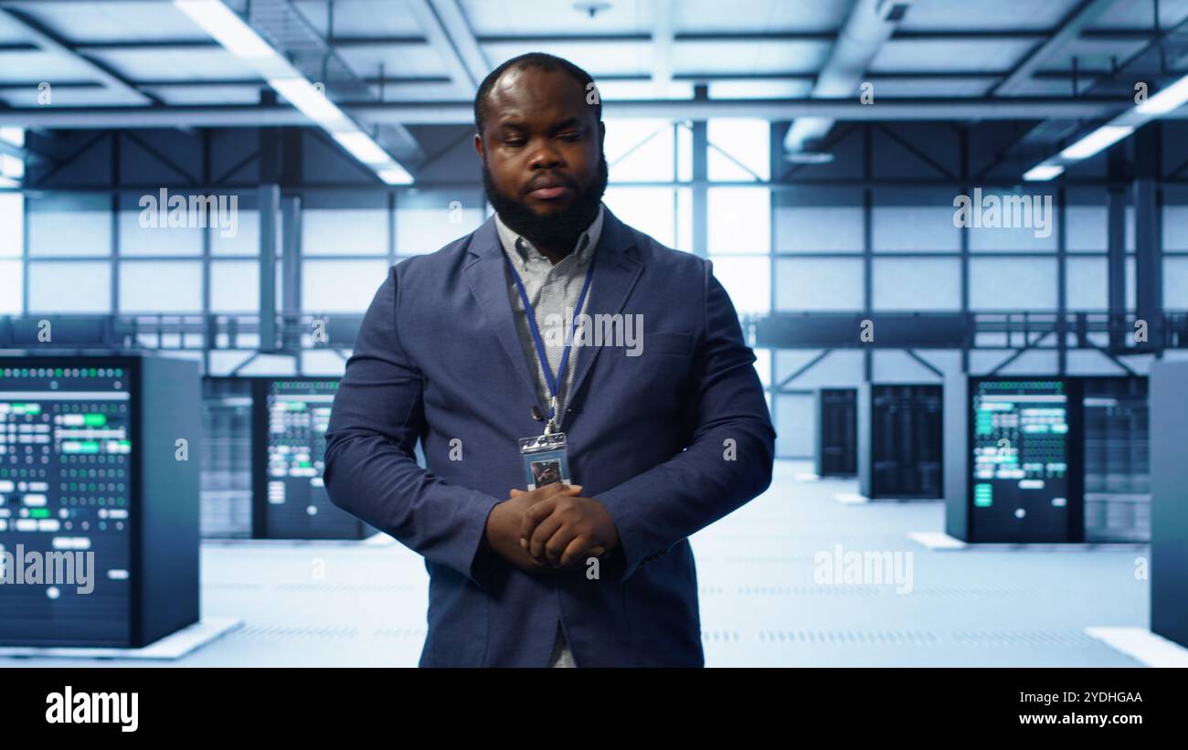 Technician walking between server rows in data center, doing yearly infrastructure inspection ...