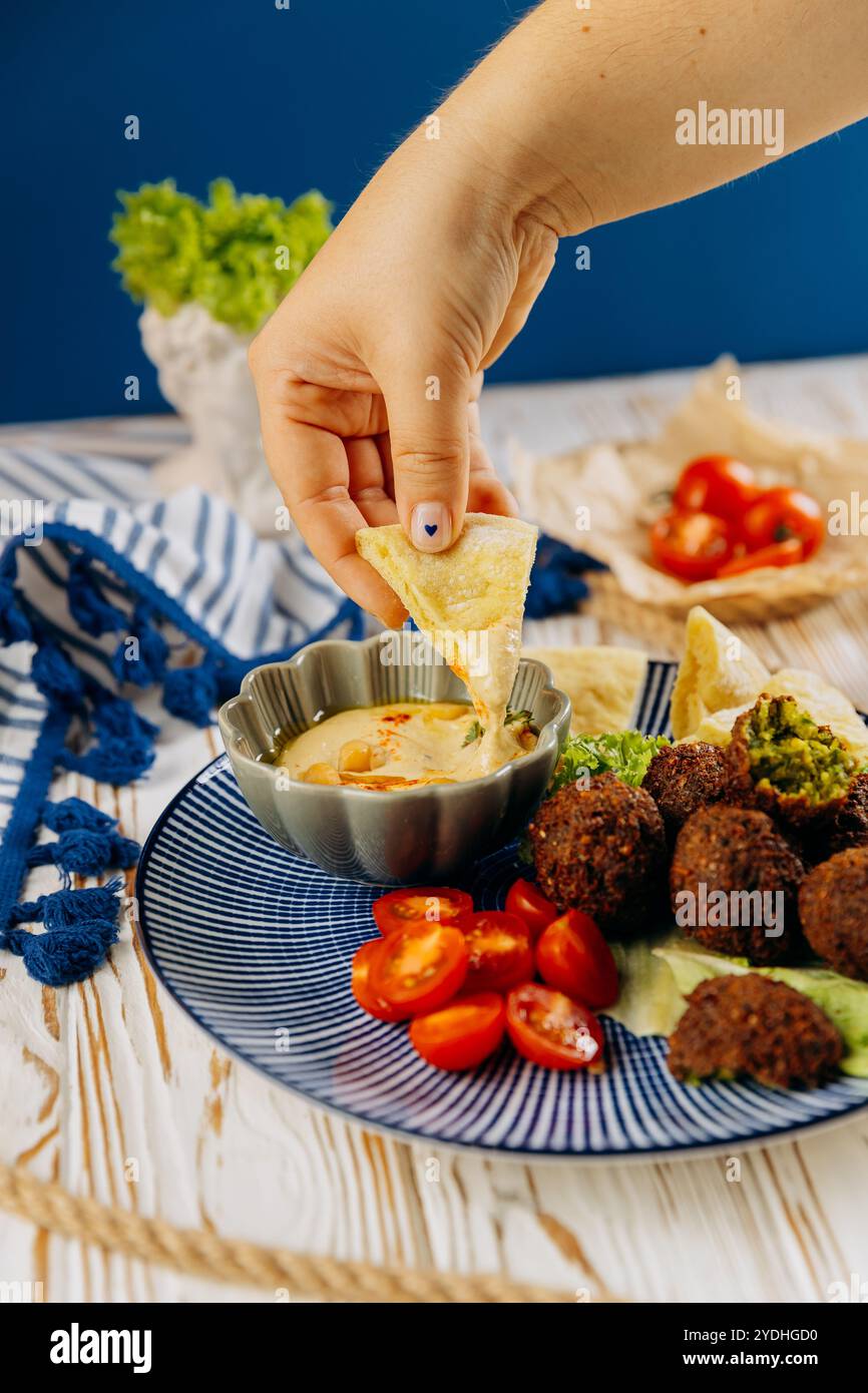 Hand dipping pita bread in creamy hummus. Perfect Middle Eastern snack ...