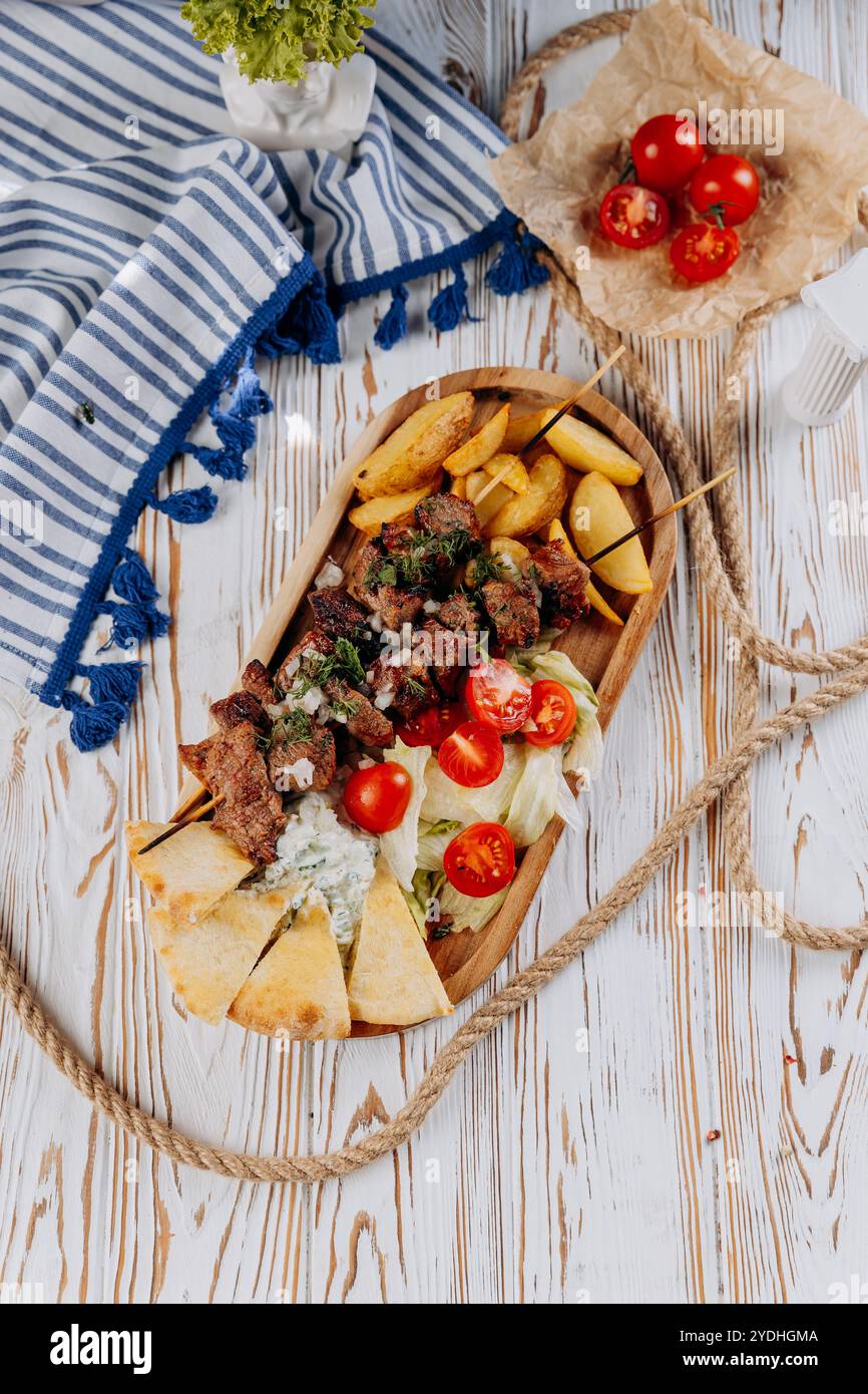 Mixed grill platter with skewers, roasted potatoes, pita, salad, and ...