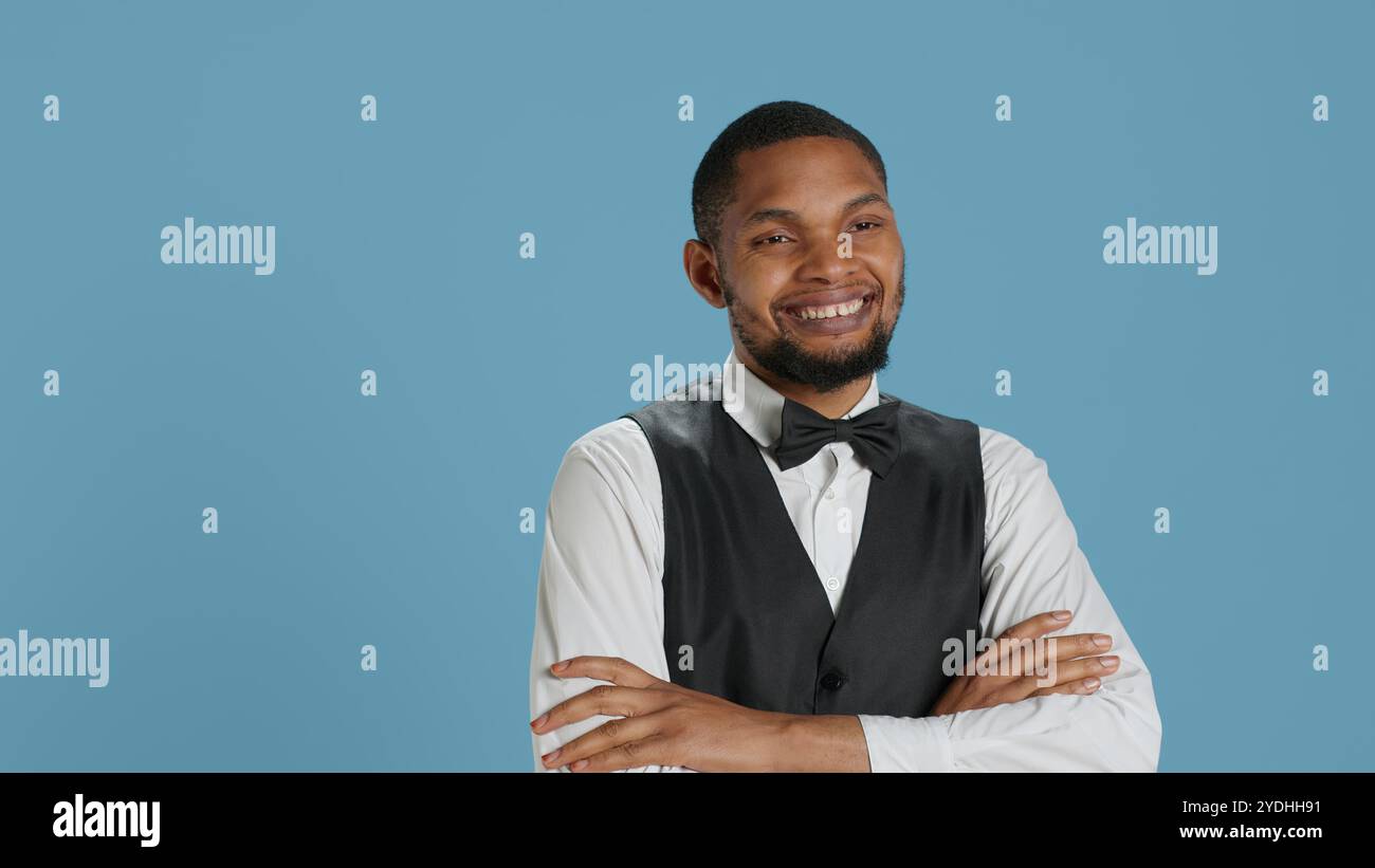 Confident cheerful hotel concierge staff poses with arms crossed in ...