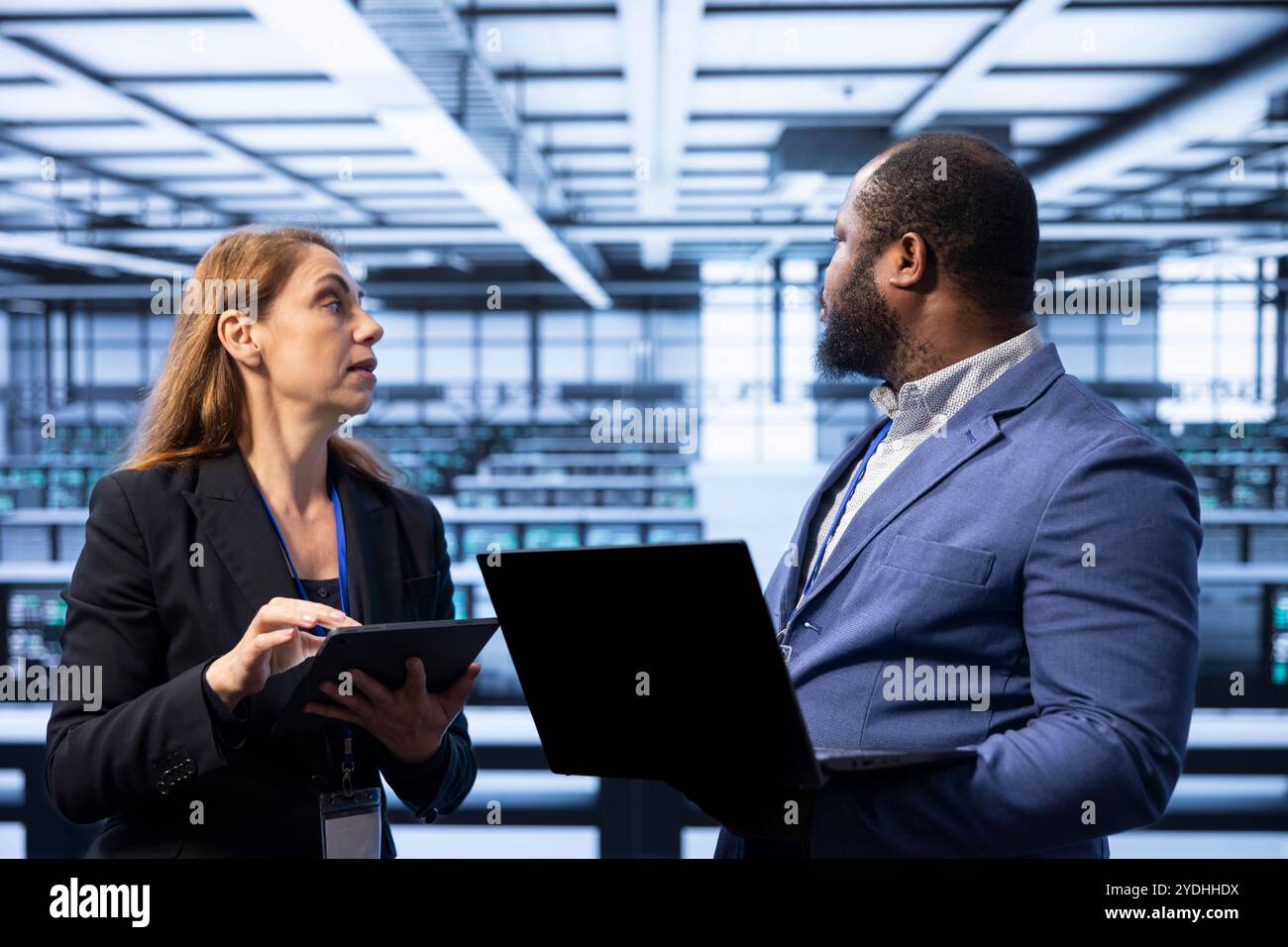 Team of developers in server hub installing newly ordered storage rigs using devices ...