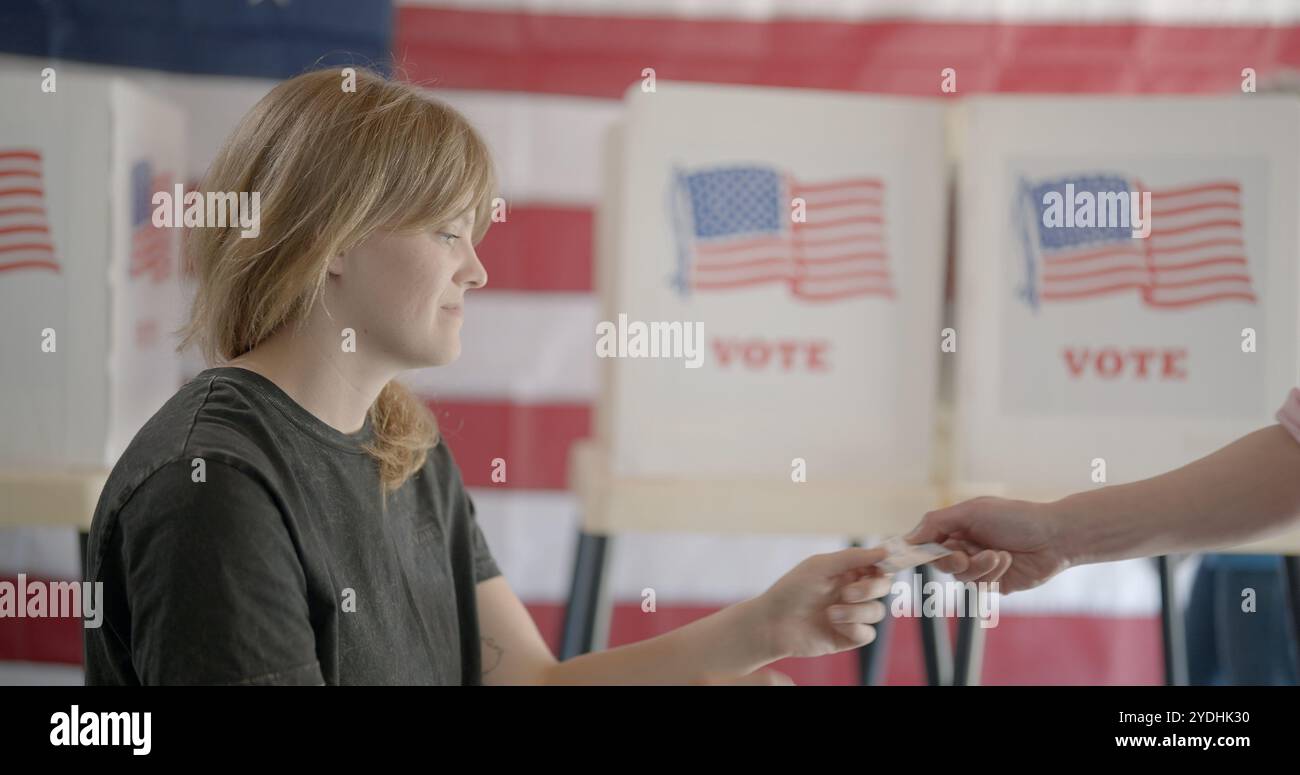 Medium shot, profile, young, red-haired woman, poll worker at voting ...