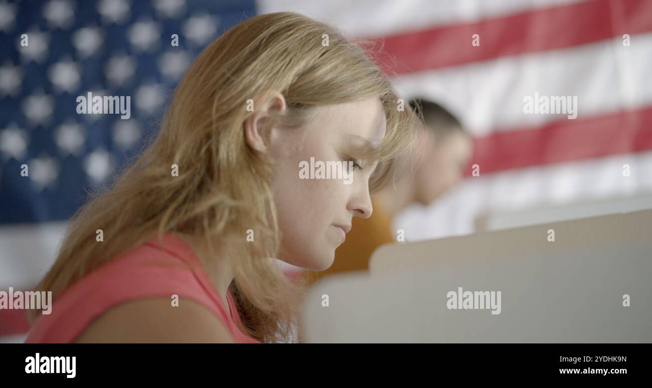 Profile, big close up, young, red-haired woman casting votes at booth ...